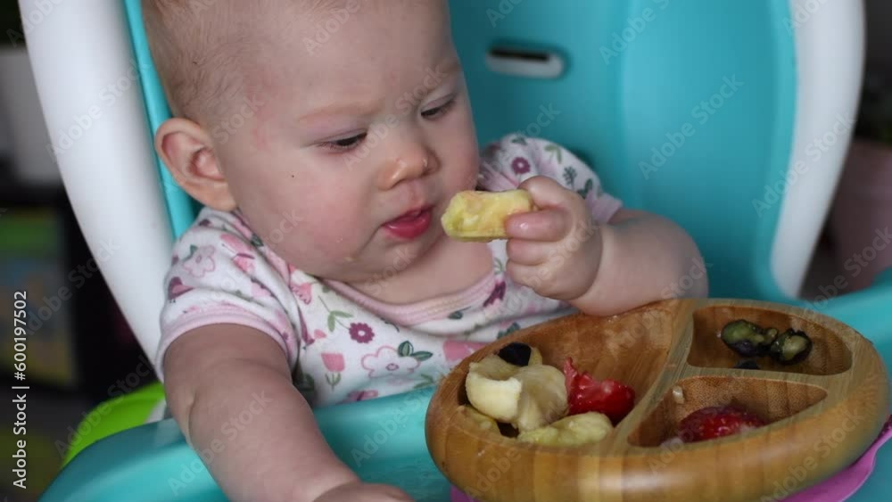 Cute baby girl learning how to feed herself and exploring food. Baby ...