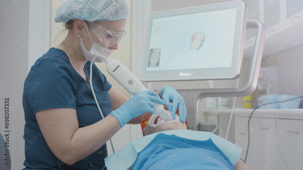 Doctor scans the patient's teeth in the clinic. The dentist holds in ...