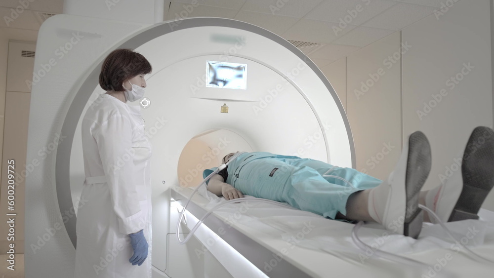 Doctor makes an MRI scan for a patient in a clinic. The girl lies in ...