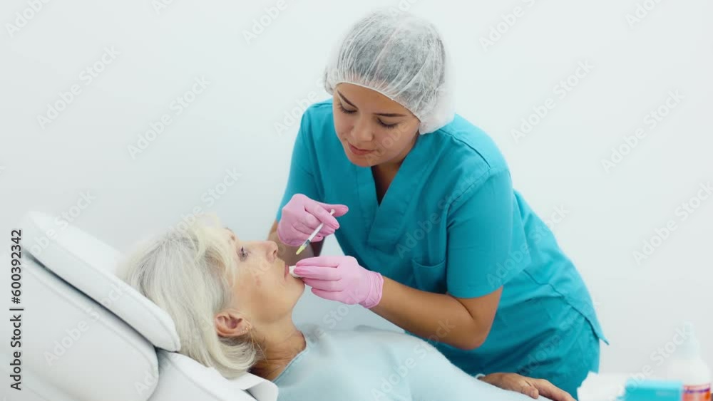Serious young woman lying on clinical chair in aesthetic cabinet during ...