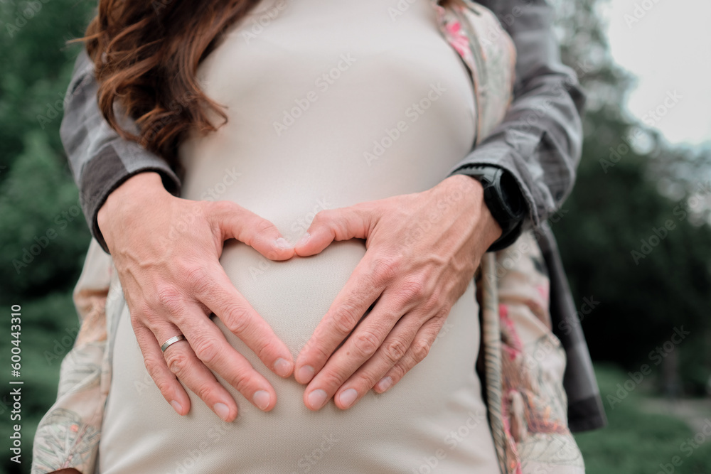 man holding belly of his pregnant wife making heart. Pregnant woman and ...