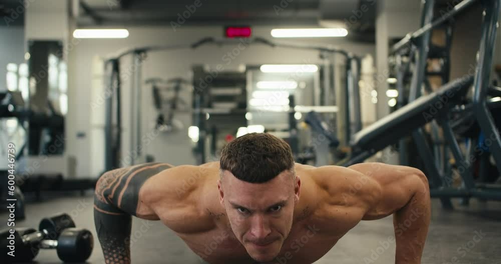 Strong athletic man trains shirtless in the gym, doing push-ups. Lean ...