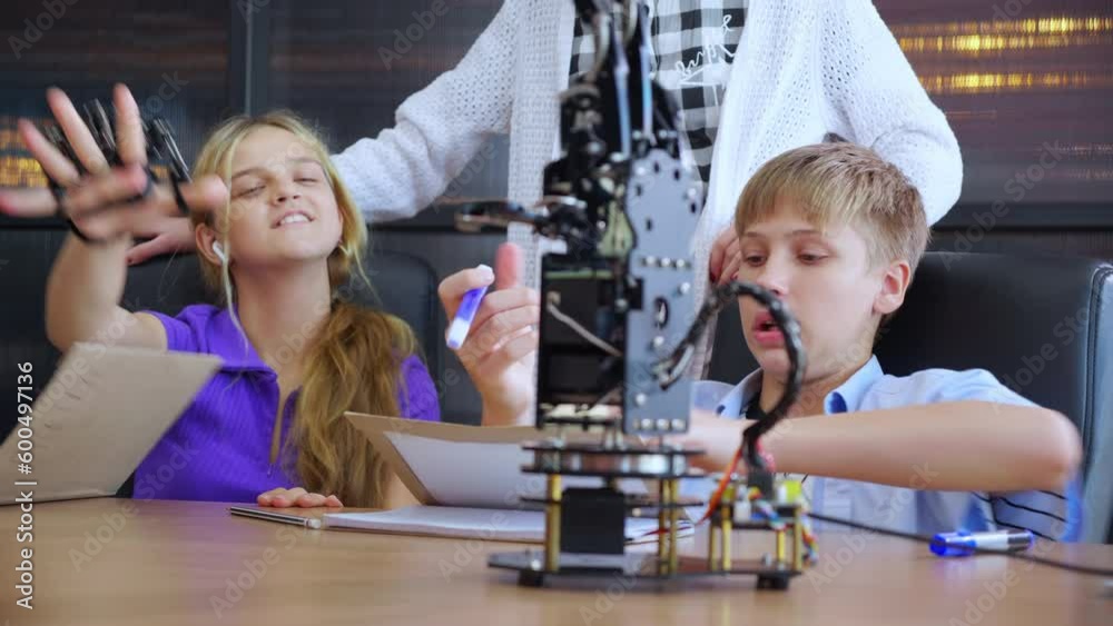 Caucasian two teenager students learning robotic arm in classroom ...