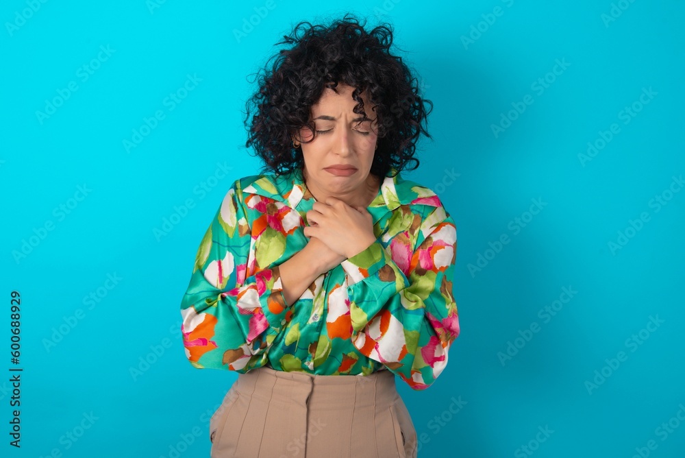 Sad young arab woman wearing colorful shirt over blue background ...