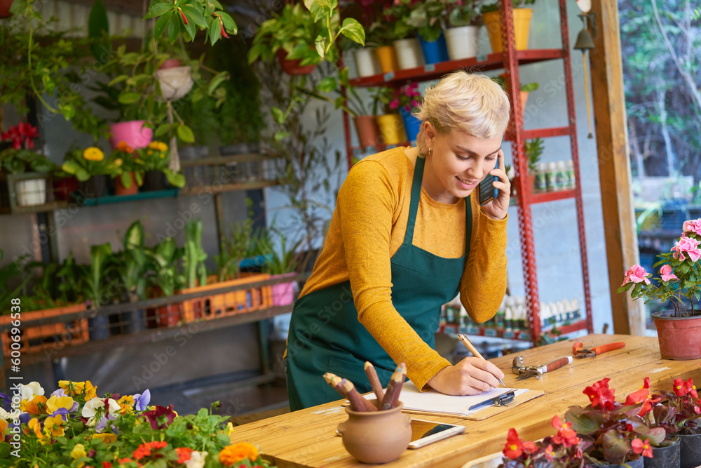 Female florist on the phone notes an order in the flower shop Stock ...