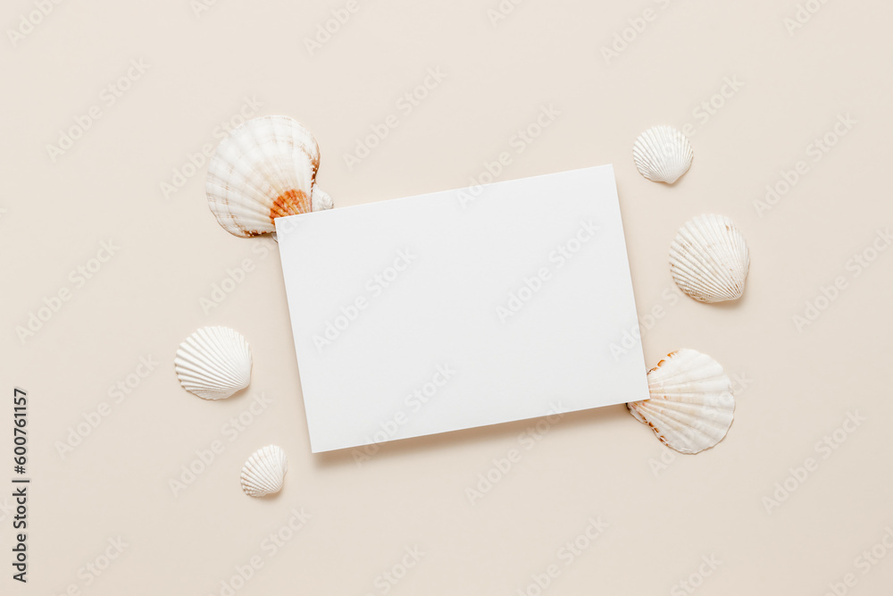 Foto de Empty paper sheet card on seashells on neutral beige background ...