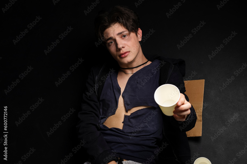 A homeless young person with bruises under their eyes in dirty ...