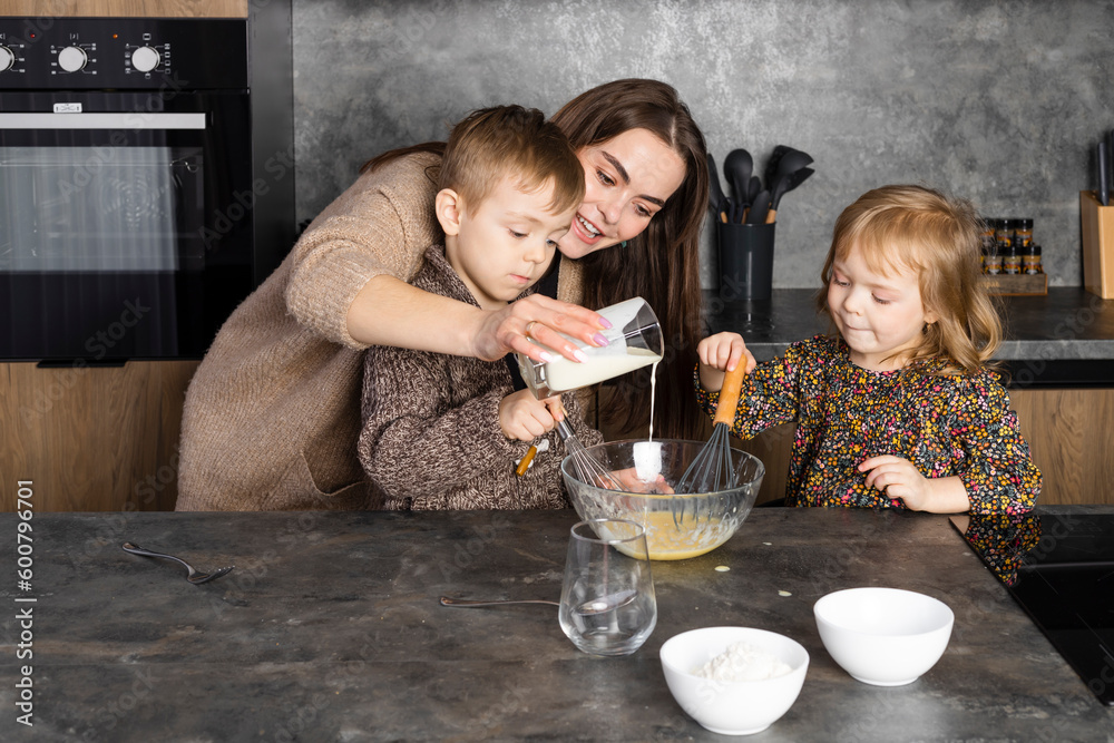Mother cooking together with her children on a modern kitchen, helping ...