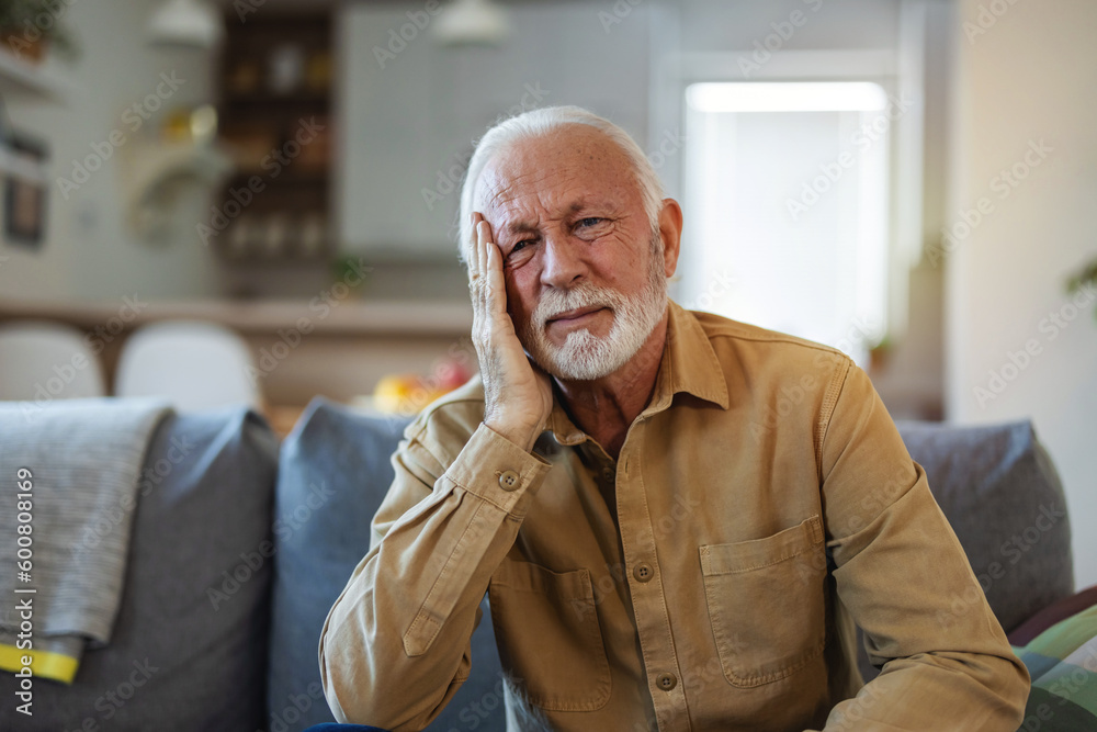 Foto de Tired, depressed senior man sitting on couch in living room ...