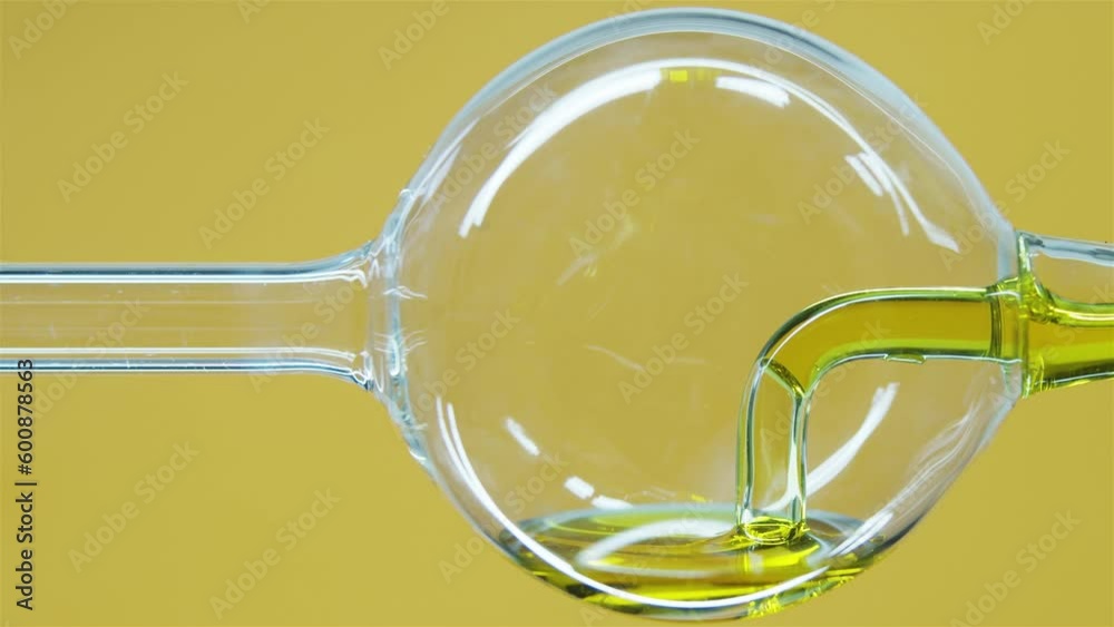 Yellow natural oil flows in a laboratory glass flask. Obtaining ...