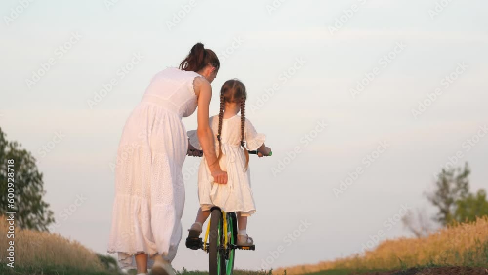 Mother teaches child girl daughter ride two-wheeled bicycle. happy ...