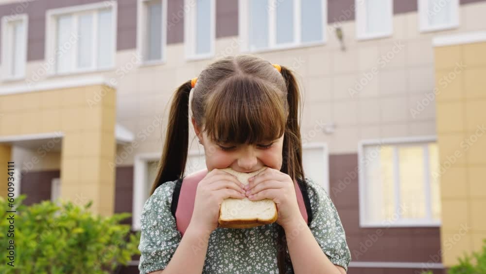 little girl with school backpack eats sandwich at recess school yard ...
