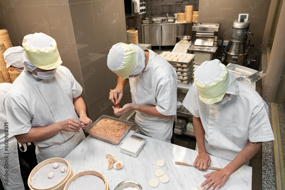 Chefs making Dim Sum in kitchen of restaurant. Chinese traditional food ...