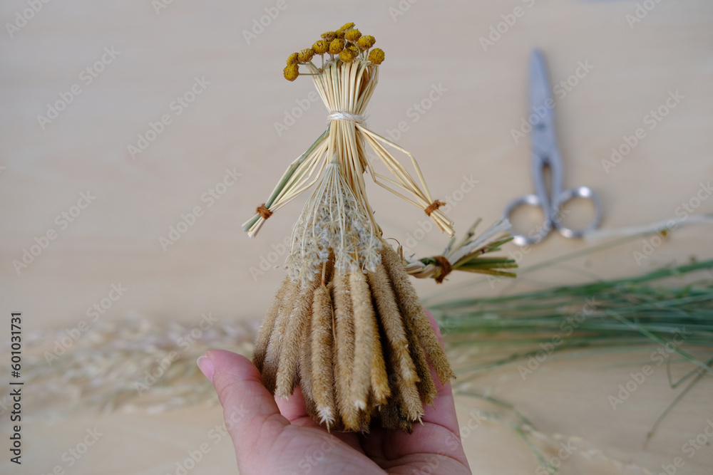 female hands holds ritual doll made of straw, grass in honor rich ...