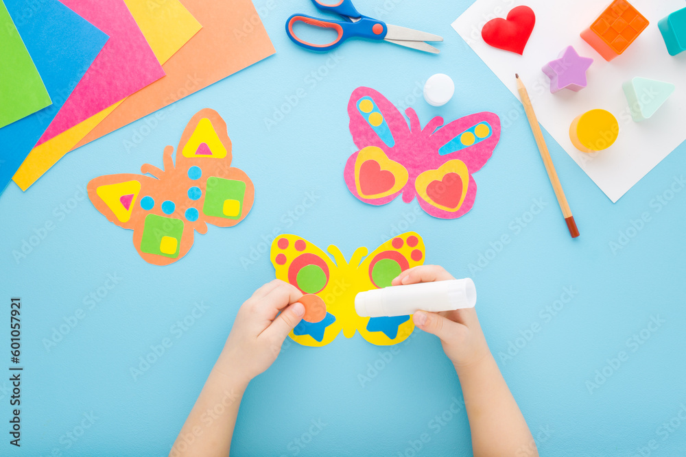 Little child hands holding glue stick and gluing colorful butterfly ... Little child hands holding glue stick and gluing colorful butterfly ...