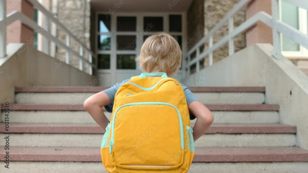 Little schoolboy with a backpack goes to school after summer holiday ...