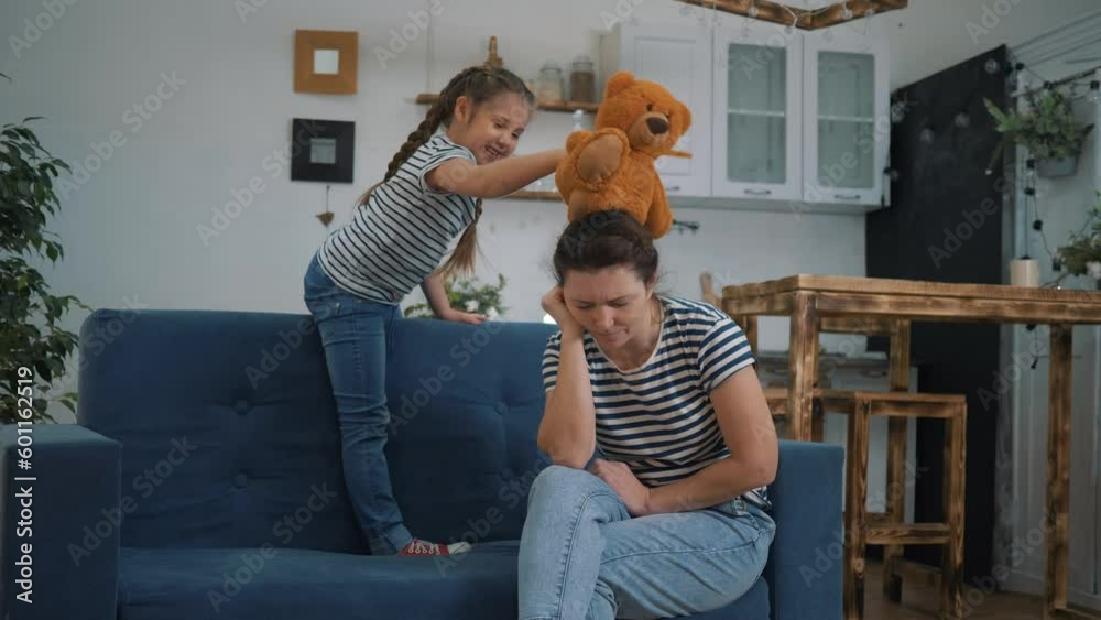 Irritated girl with sore head. Daughter screams and plays with teddy ...