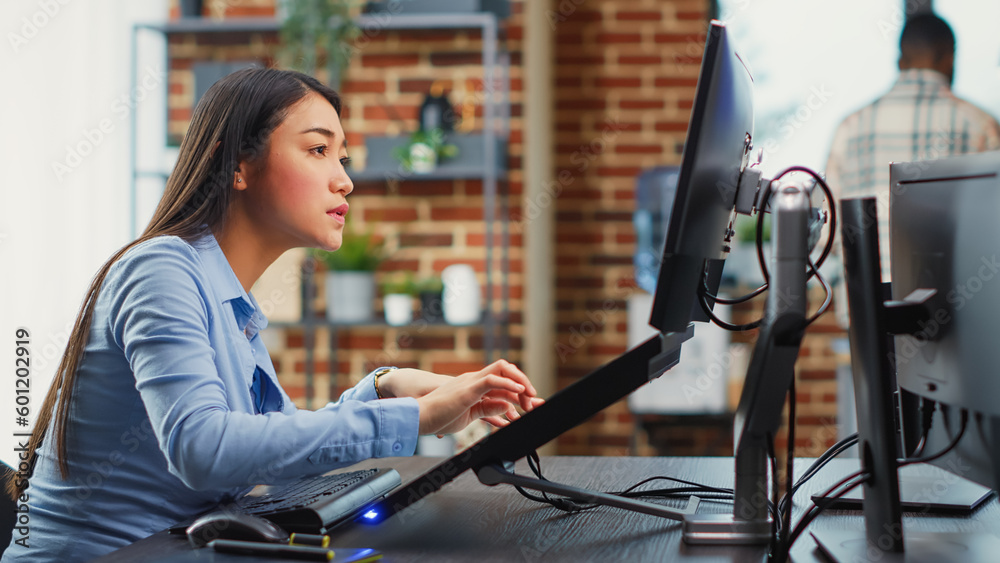 Asian female engineer using touchscreen display to create game interface on professional ...