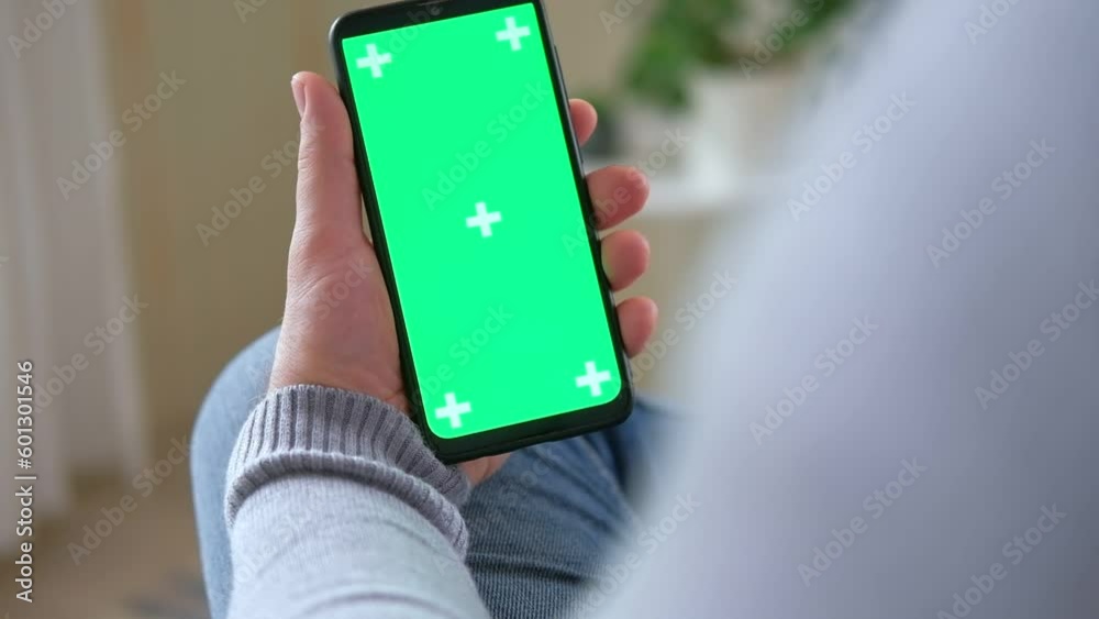 Young man holding smartphone green mock-up screen in hand. Male person using chroma key mobile ...