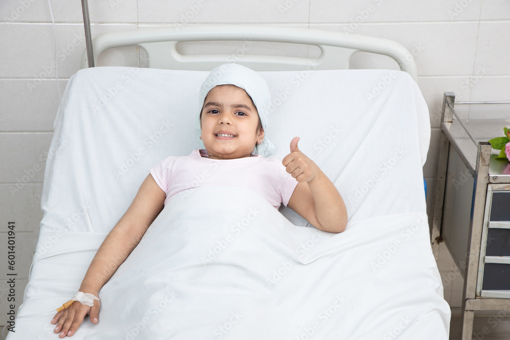 Smiling little girl child patient lying at hospital bed do thumbs up ...