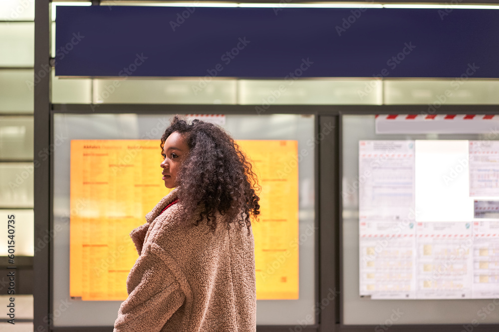 Back view of young curly girl looking distance while standing in front ...