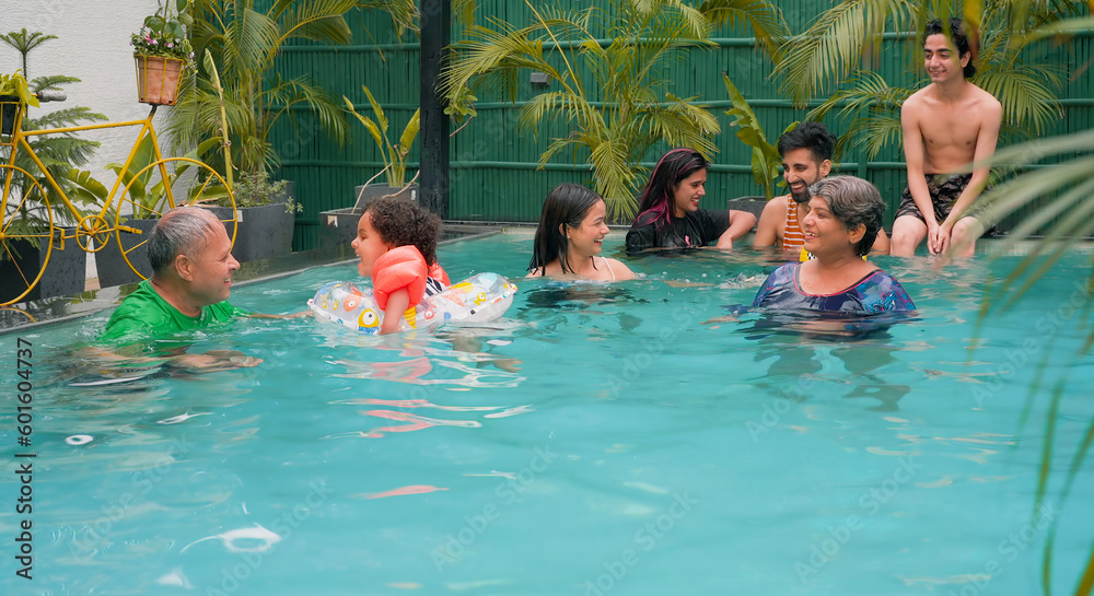 Happy Indian group family in swimming pool enjoy summer vacation picnic ...