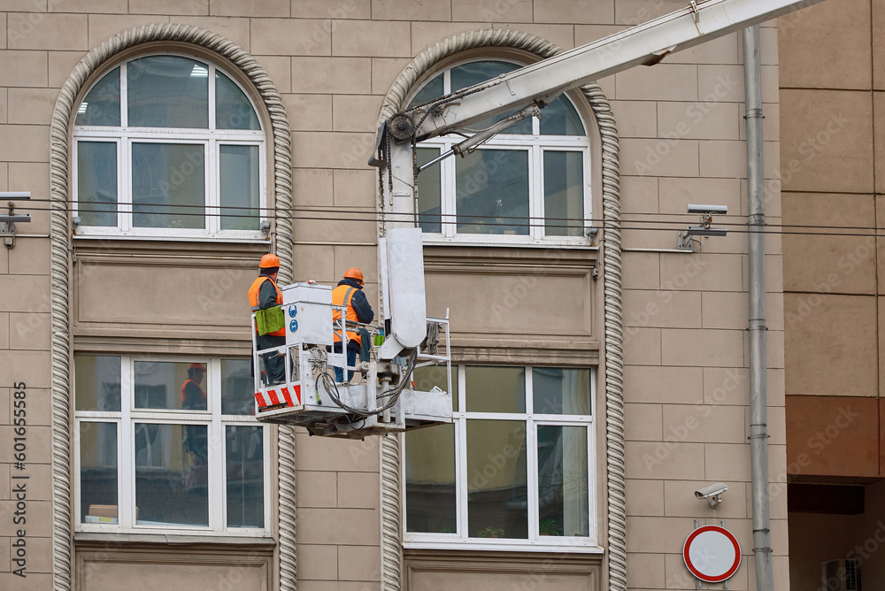 Cleaning team in aerial platform washing window and facade of historic ...