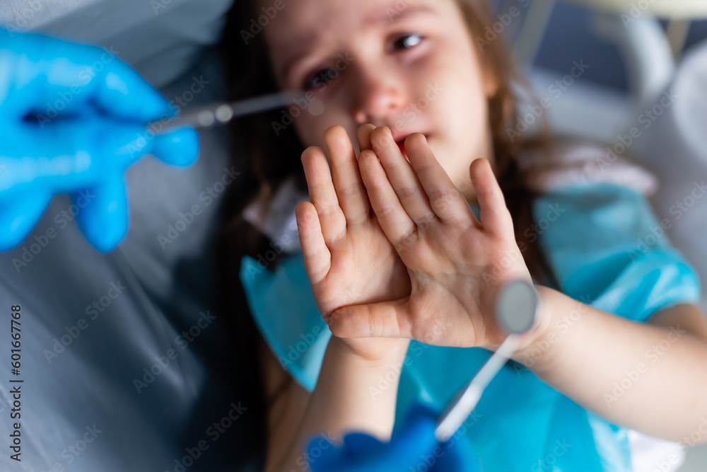 little brunette girl at the reception is crying, afraid. Pediatric ...