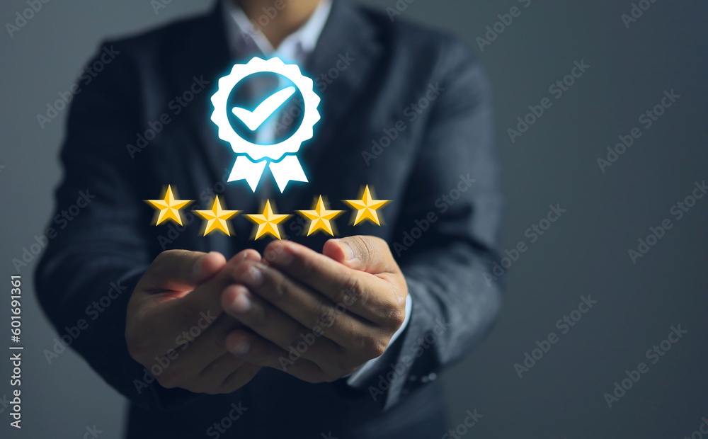 A businessman holding up a quality guarantee mark and five stars signifies certification for iso ...