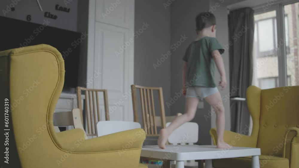 little boy kid jumping chairs armchairs table indoors living-room ...