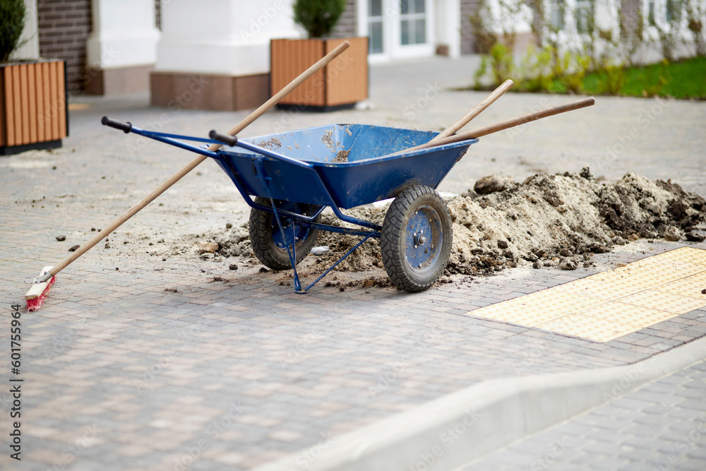 blue construction wheelbarrow with shovels. Blue iron wheelbarrow and ...