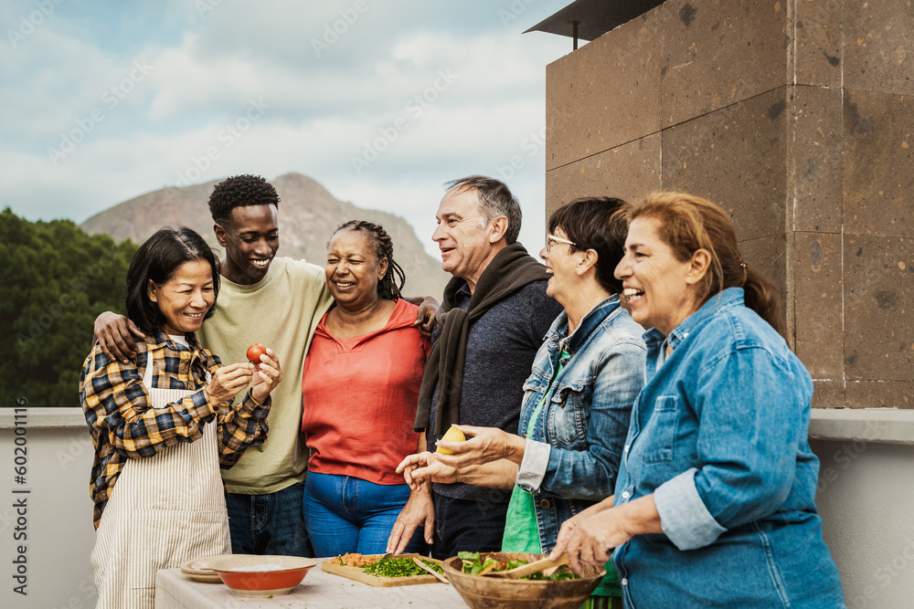 Multi generational friends having fun cooking together at house rooftop ...