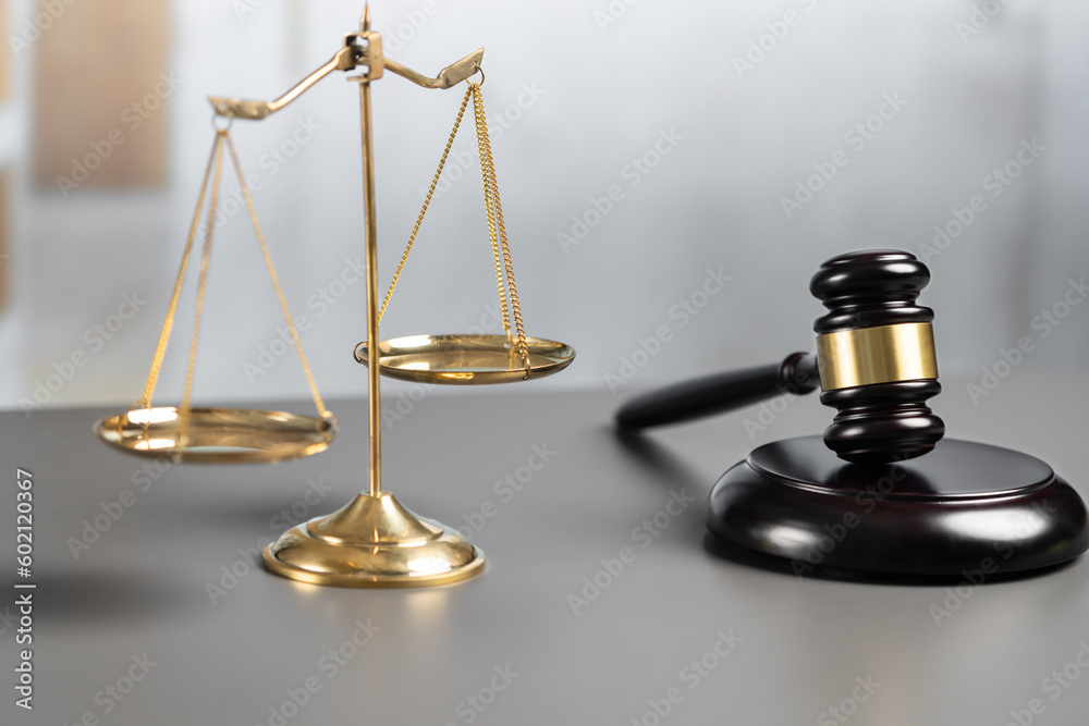 Shiny golden balanced scale and wooden gavel in court library ...