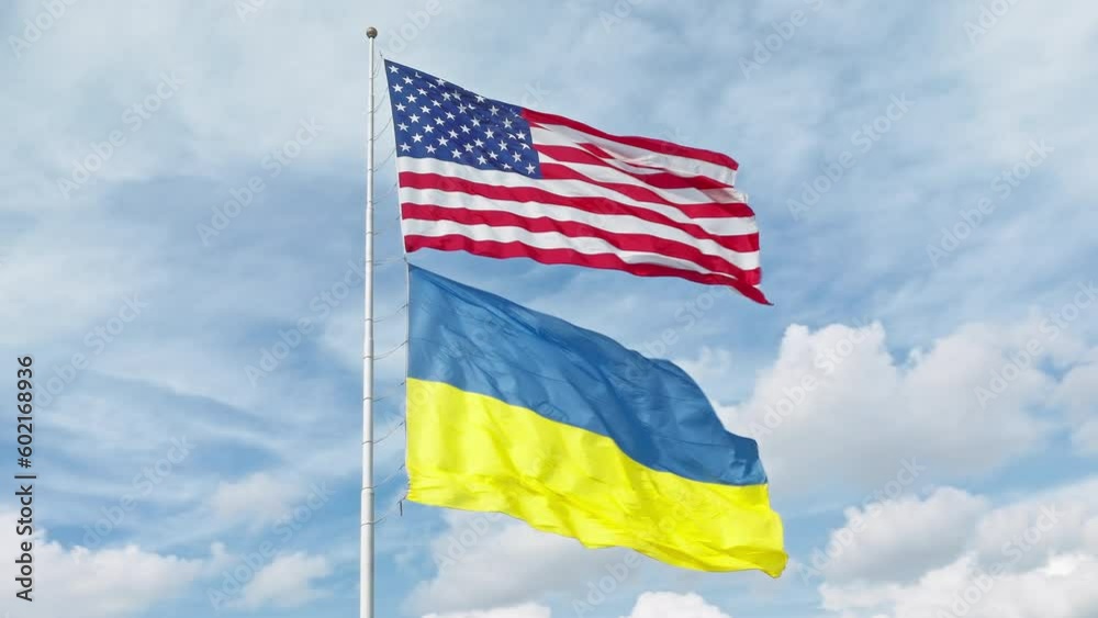 Cinematic aerial of Large American Flag and flag of Ukraine flies in ...