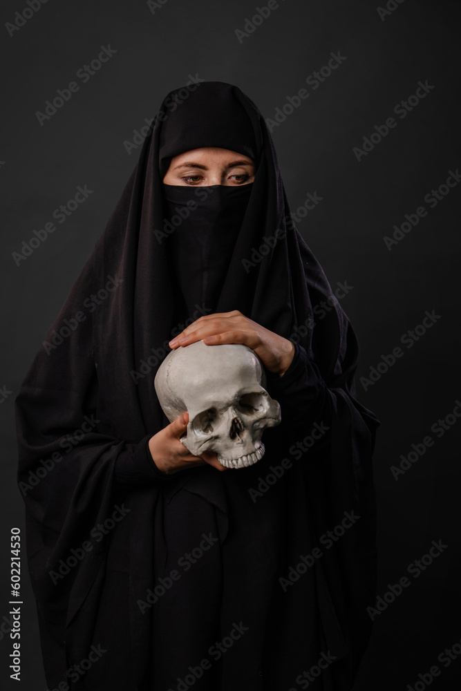 Portrait of a young, adult woman in a black burqa with a hidden face ...