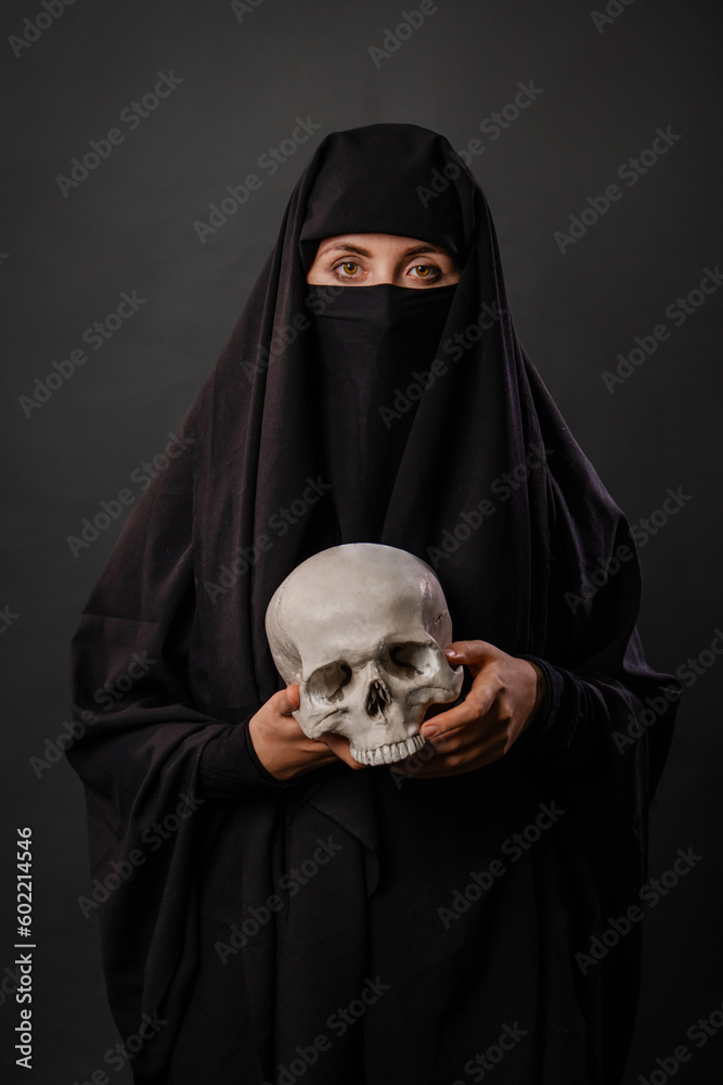 Portrait of a young, adult woman in a black burqa with a hidden face ...