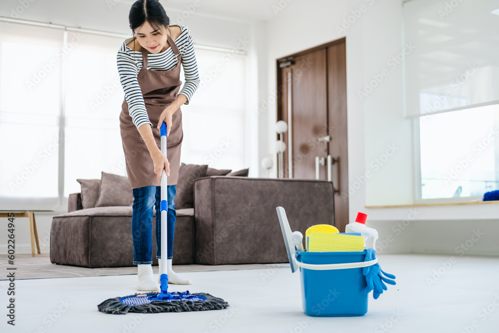 Asian woman mopping tile floor at living room while doing cleaning at ...
