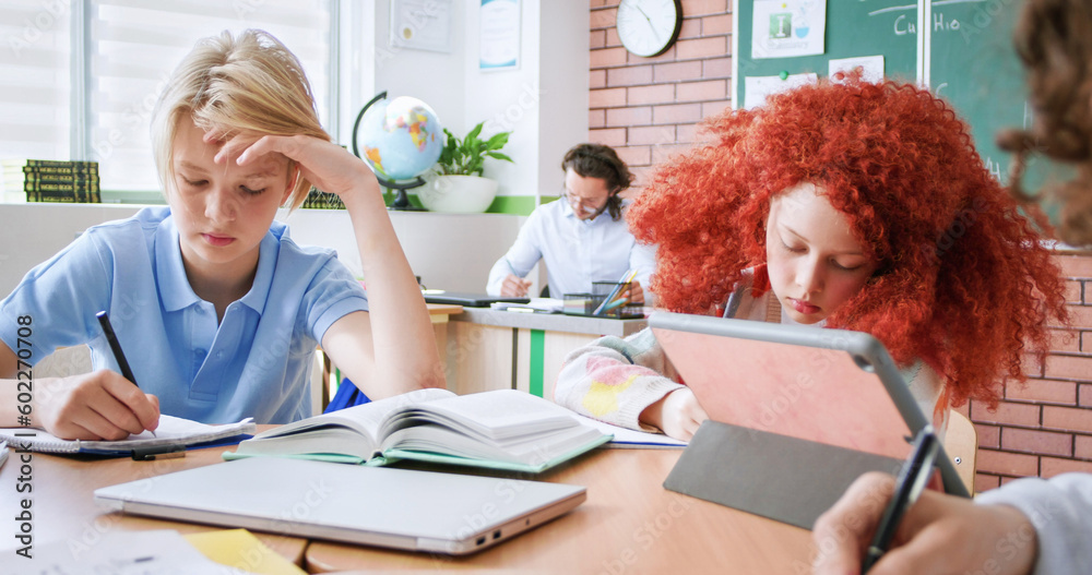 Caucasian kids studying at classes and writing exercise in copybooks ...