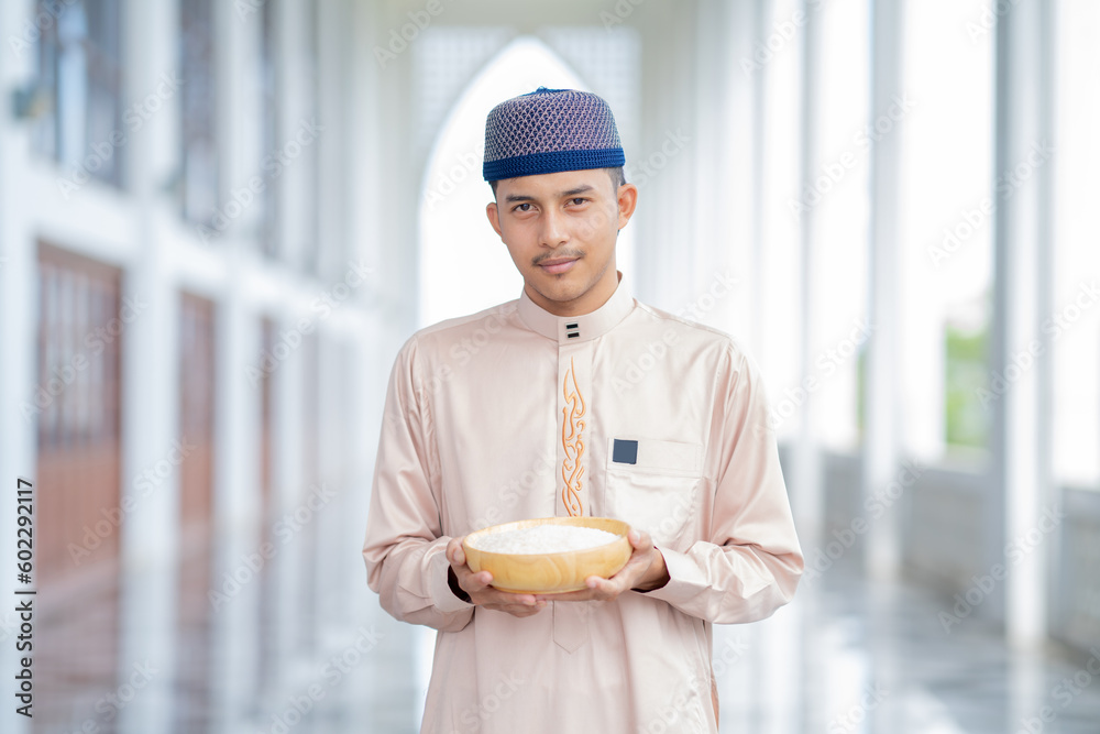 Muslim Hands are holding a wooden bowl of rice grains for zakat, an ...