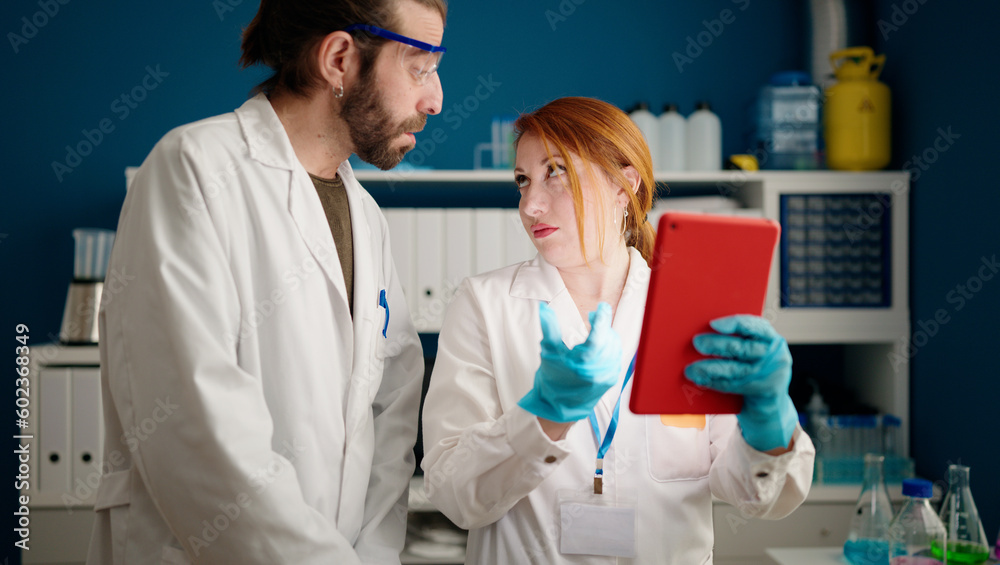 Man and woman wearing sciencist uniform using touchpad at laboratory ...