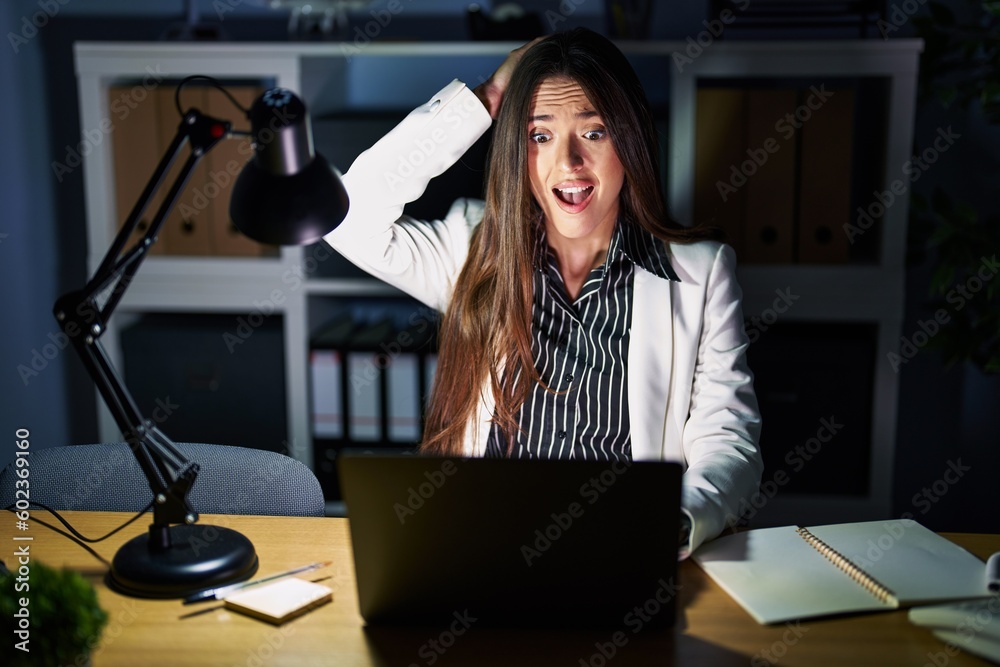 Young brunette woman working at the office at night with laptop crazy ...
