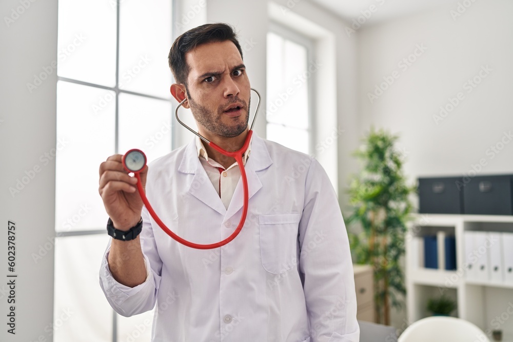 Young hispanic doctor man with beard holding stethoscope auscultating ...