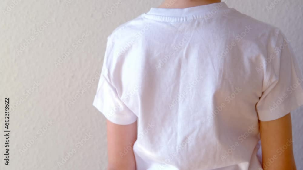 back of boy, child 8-10 years old in a white t-shirt grabbed a sore ...