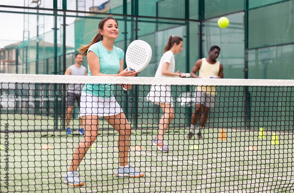 Emotional young adult woman training padel at warm sunny day at group ...