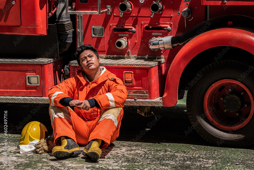 The firefighter tired from rescuing a victim from a fire situation sits ...