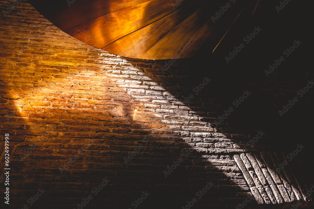 Detail of copper spiral staircase with red brick wall background and ...