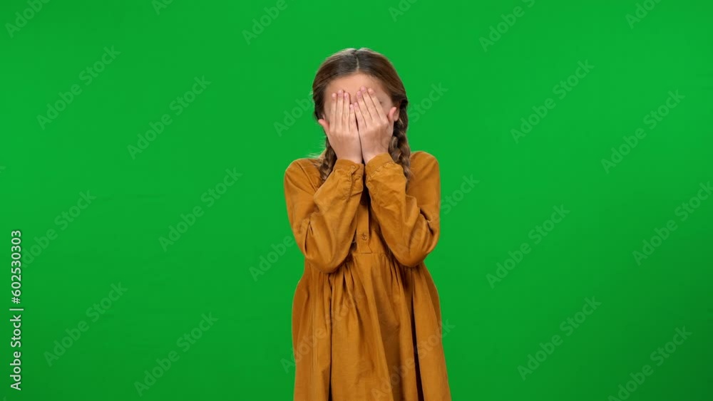 Scared girl covering face with hands looking at camera standing at ...