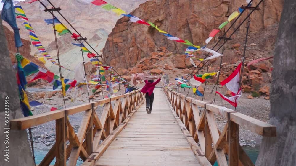 Girl holding shawl and running on a bridge over a clear blue Tsarap ...