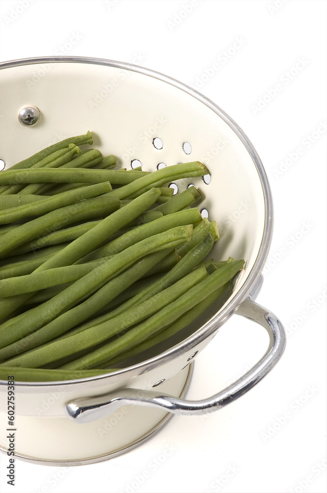 Kitchen collander filled with green beans brightly lit on isolated ...