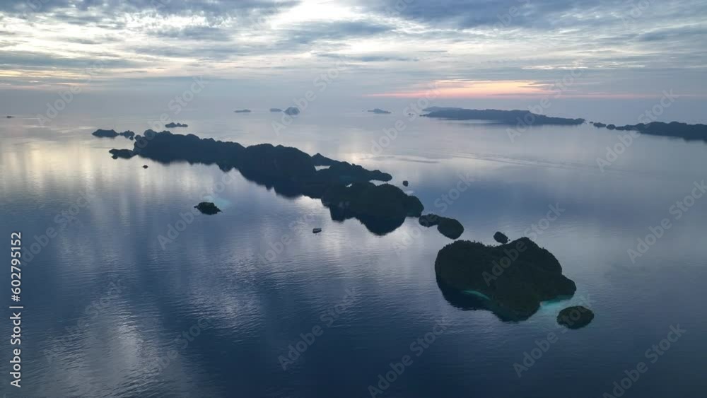 At sunrise, calm seas surround limestone islands that rise from Raja ...
